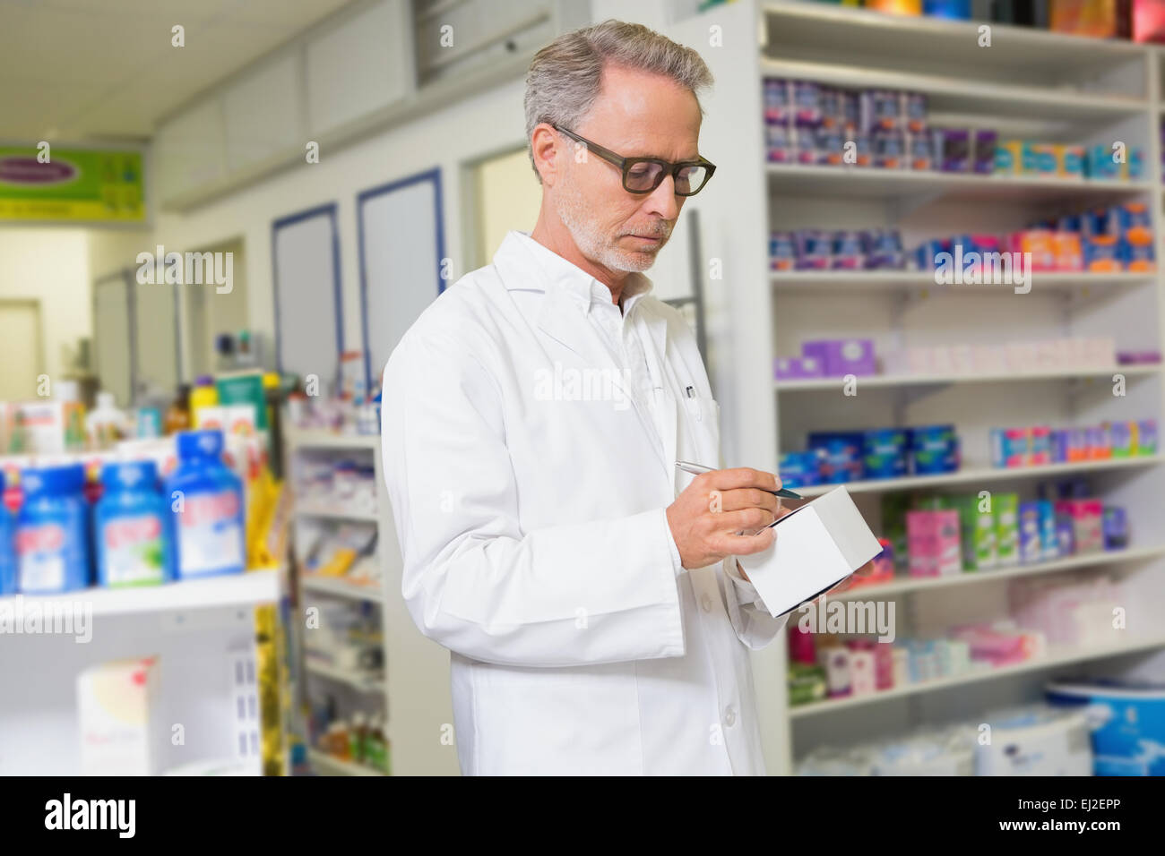 Focused pharmacist writing on box of medicine Stock Photo - Alamy