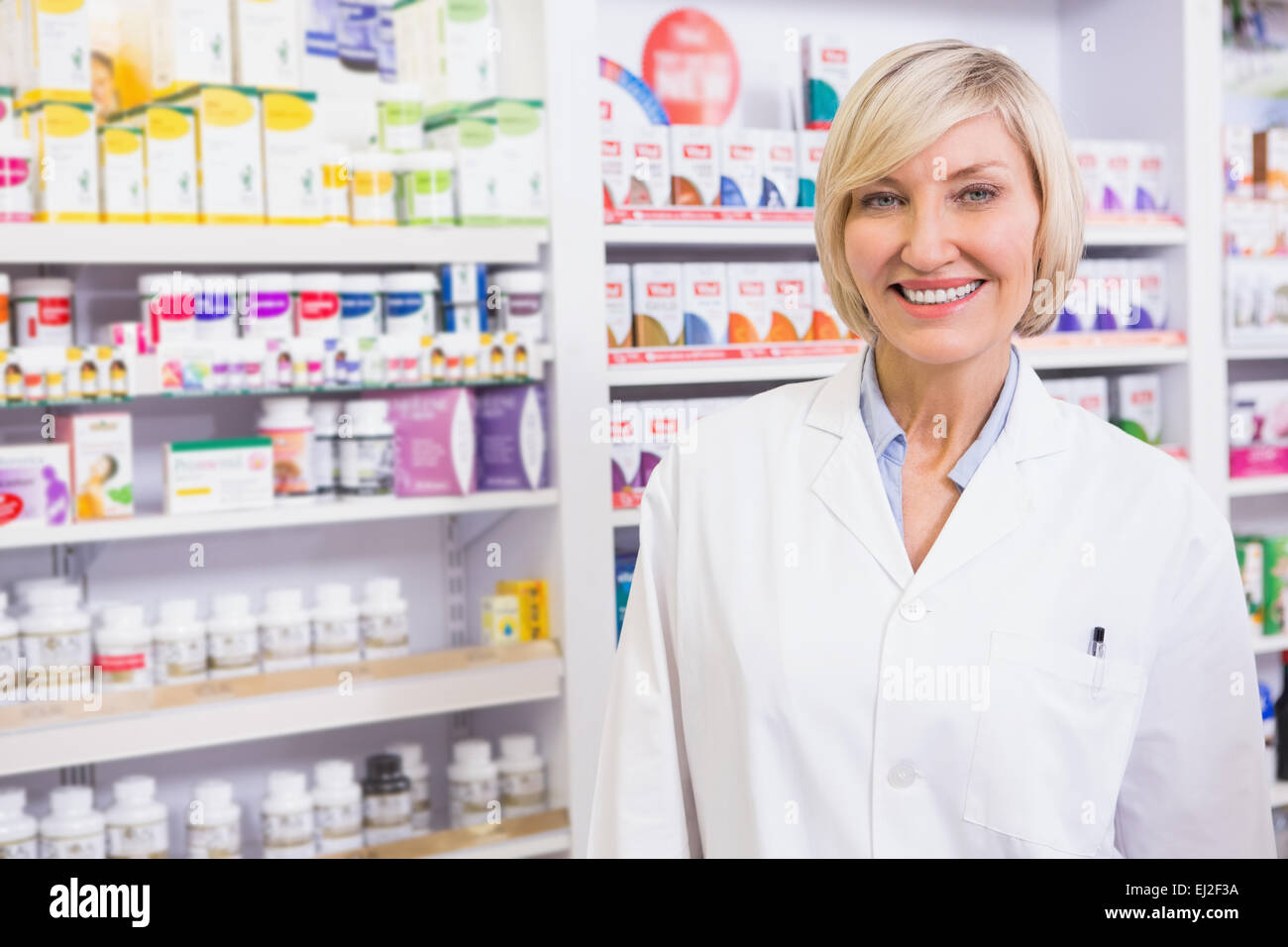 Smiling blonde pharmacist posing in lab coat Stock Photo - Alamy