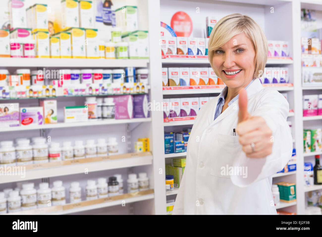 Positive blonde pharmacist with thumb up Stock Photo - Alamy