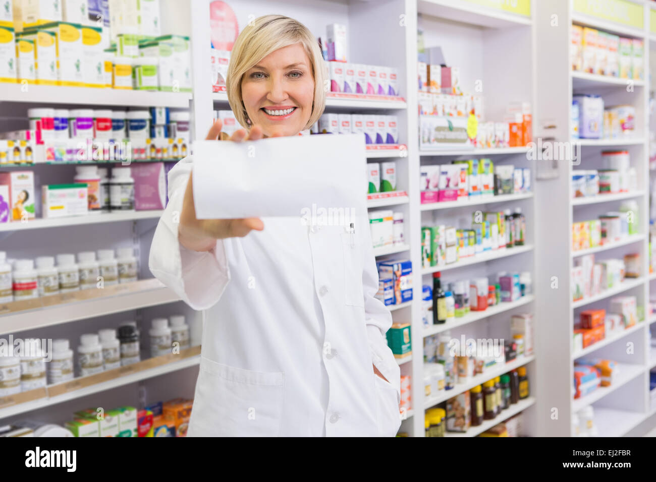 Smiling pharmacist showing paper at camera Stock Photo - Alamy