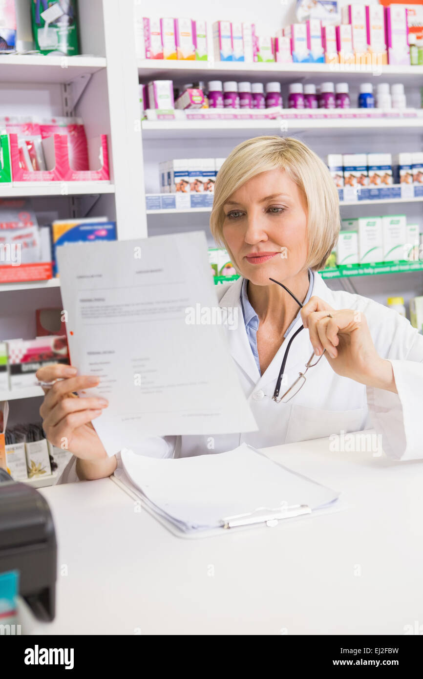 Smiling pharmacist thinking and reading prescription Stock Photo - Alamy