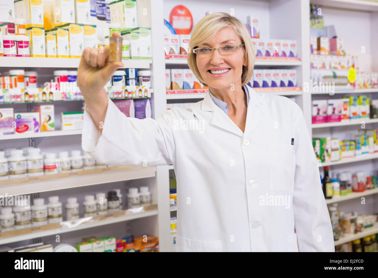 Smiling pharmacist showing medication at camera Stock Photo - Alamy