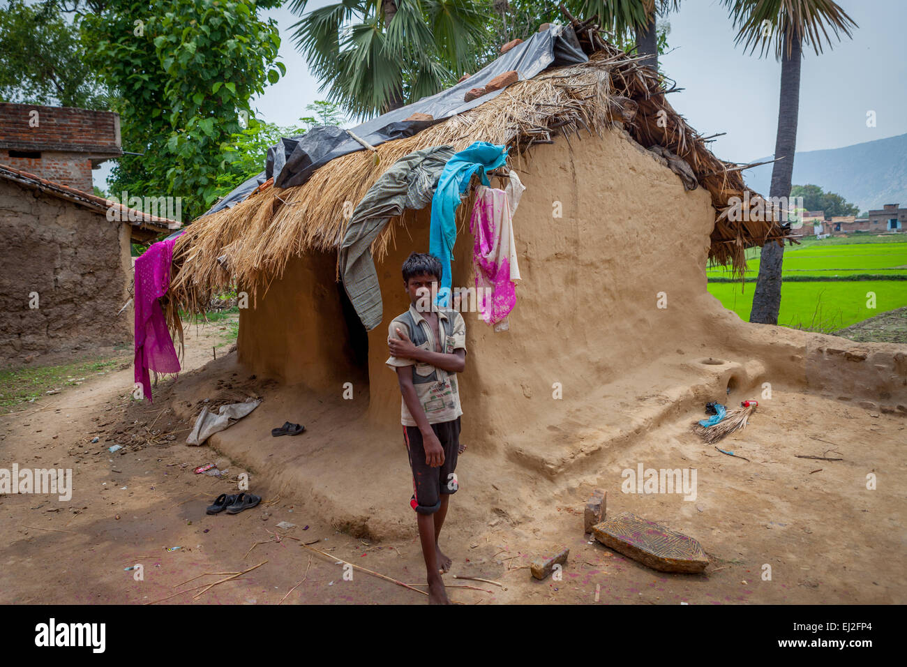 Boy stands in front of an earthy hut, a common type of settlement in ...