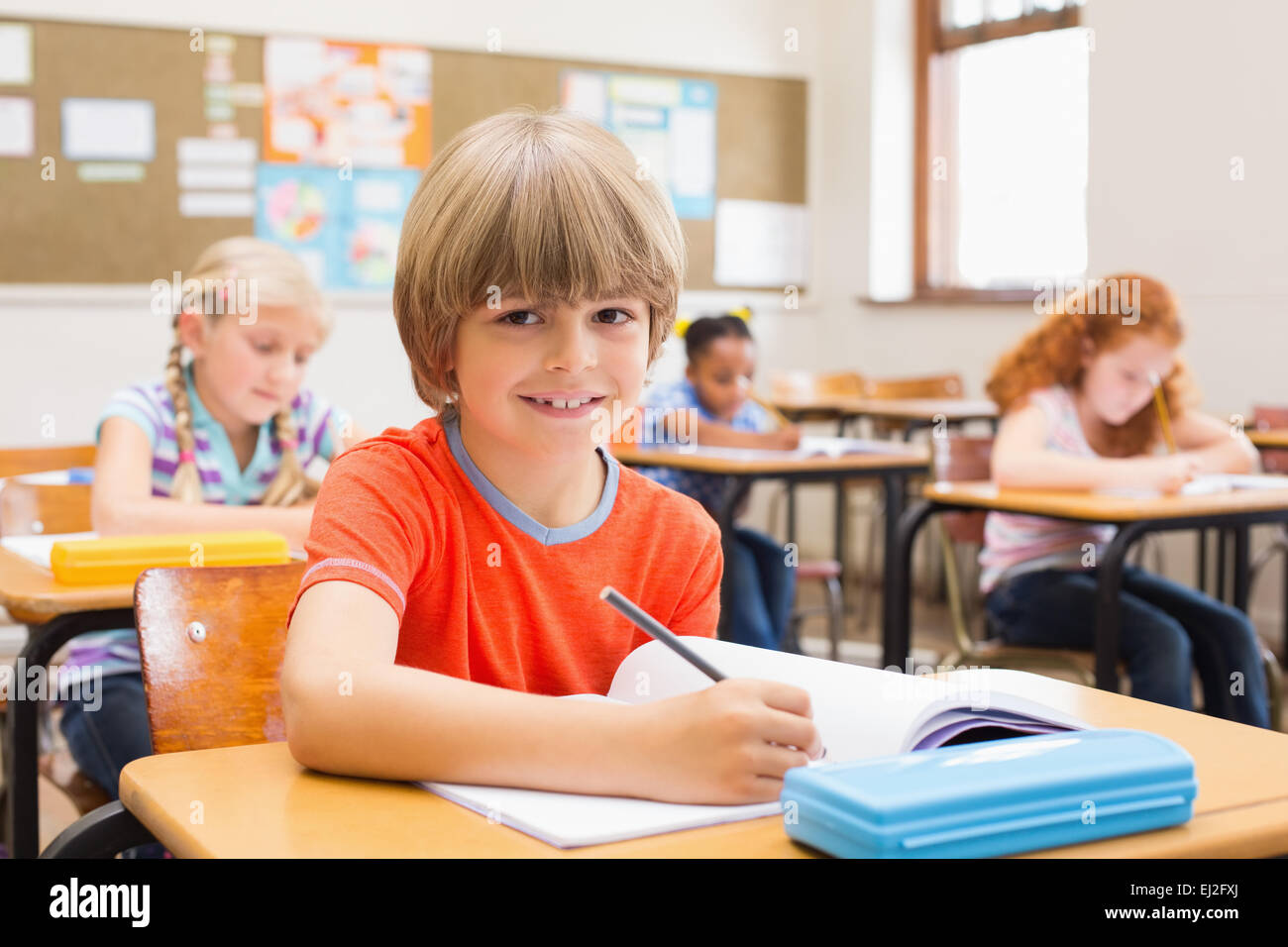 Cute pupils writing at desk in classroom Stock Photo - Alamy
