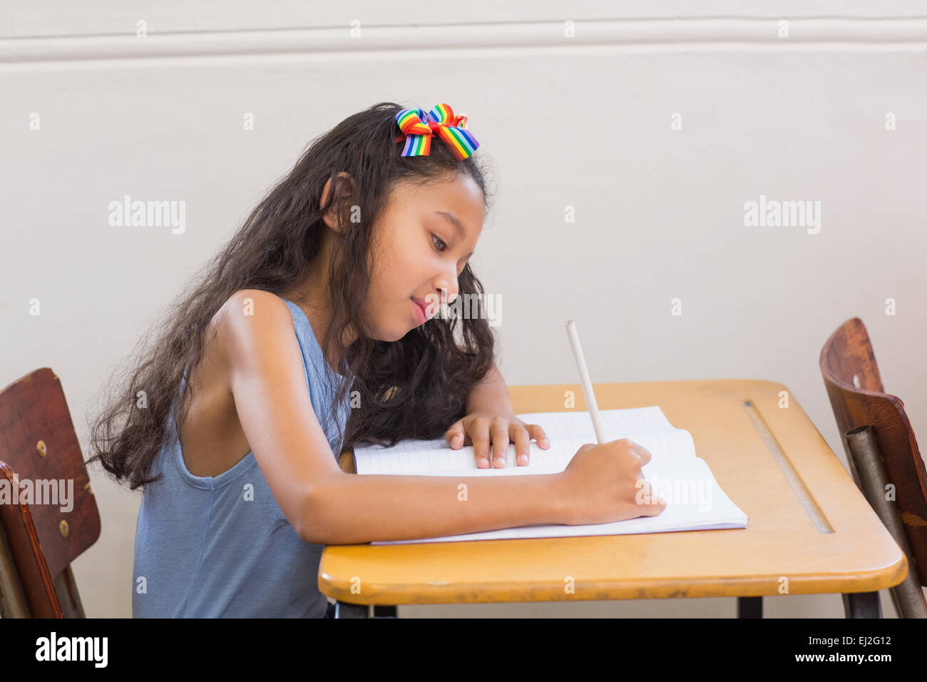 Cute pupils writing at desk in classroom Stock Photo - Alamy