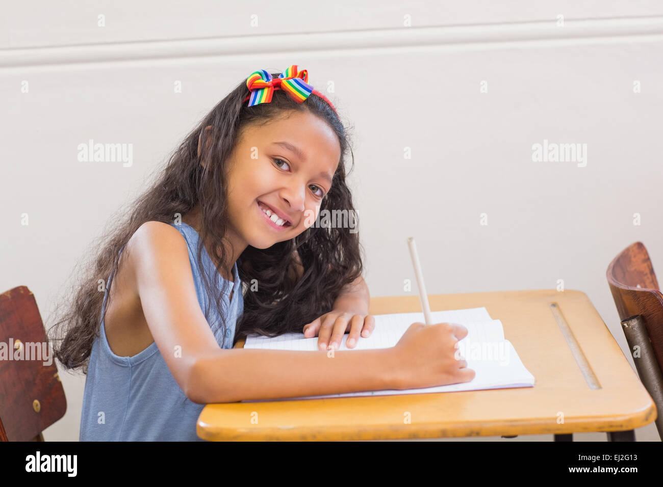 Cute pupils writing at desk in classroom Stock Photo - Alamy