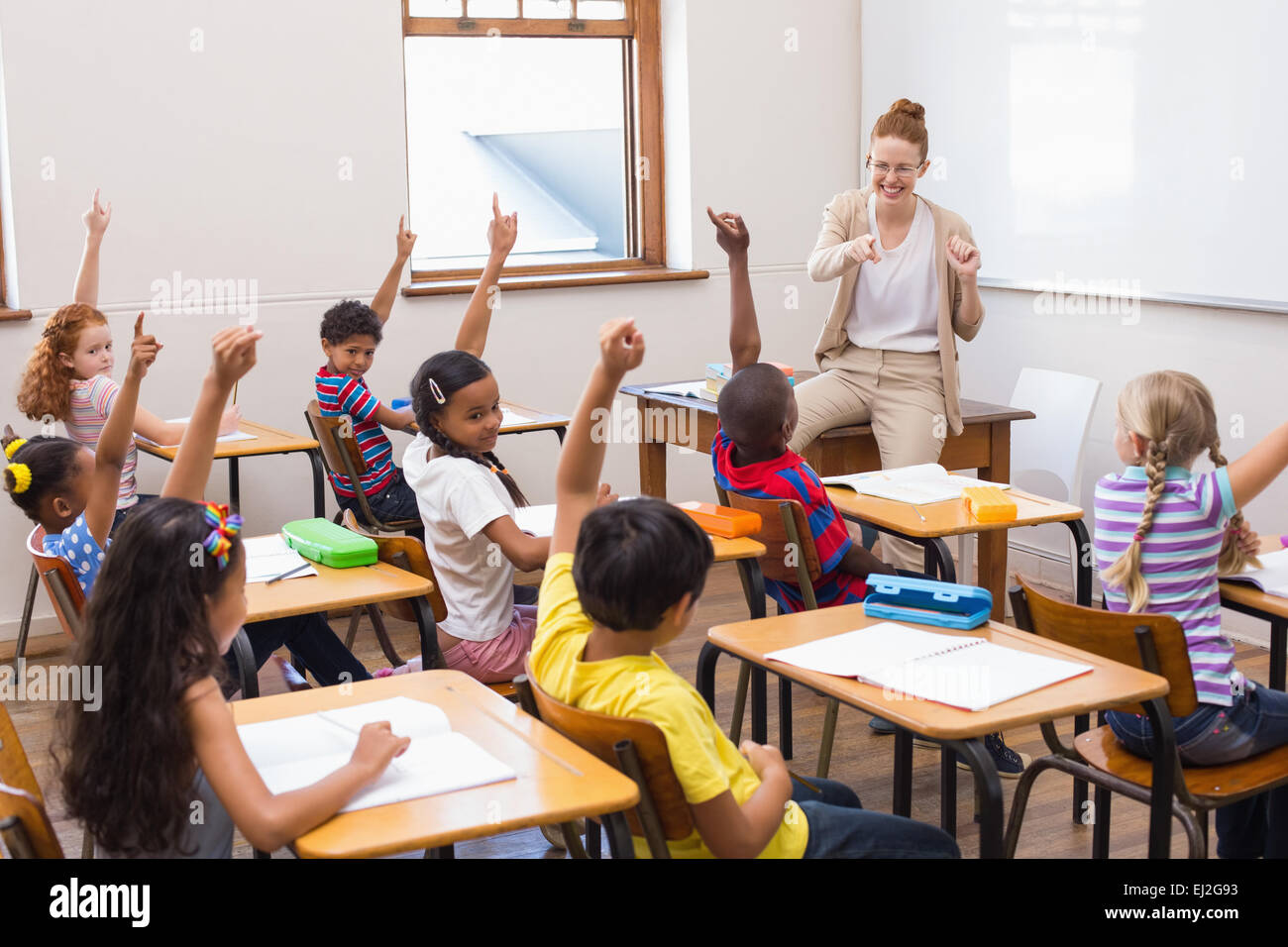 Pupils raising hand in classroom Stock Photo - Alamy