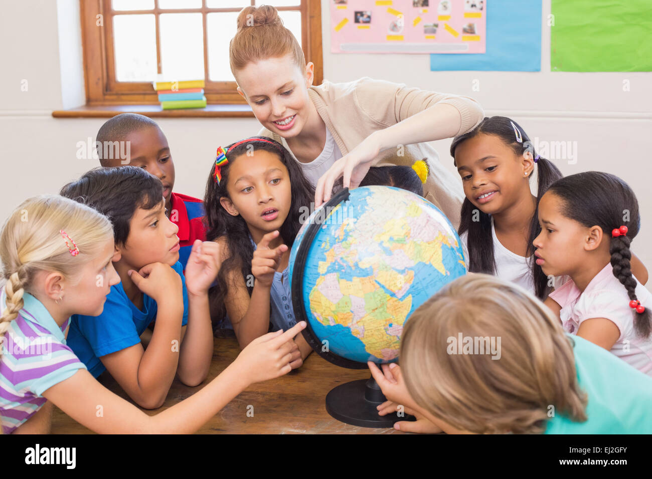 Cute pupils and teacher in classroom with globe Stock Photo - Alamy