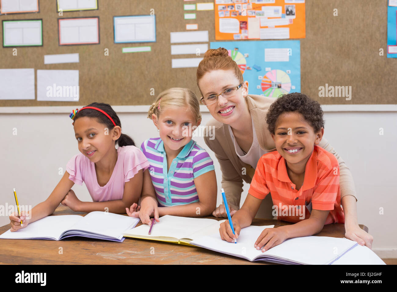 Teacher and pupils working at desk together Stock Photo - Alamy