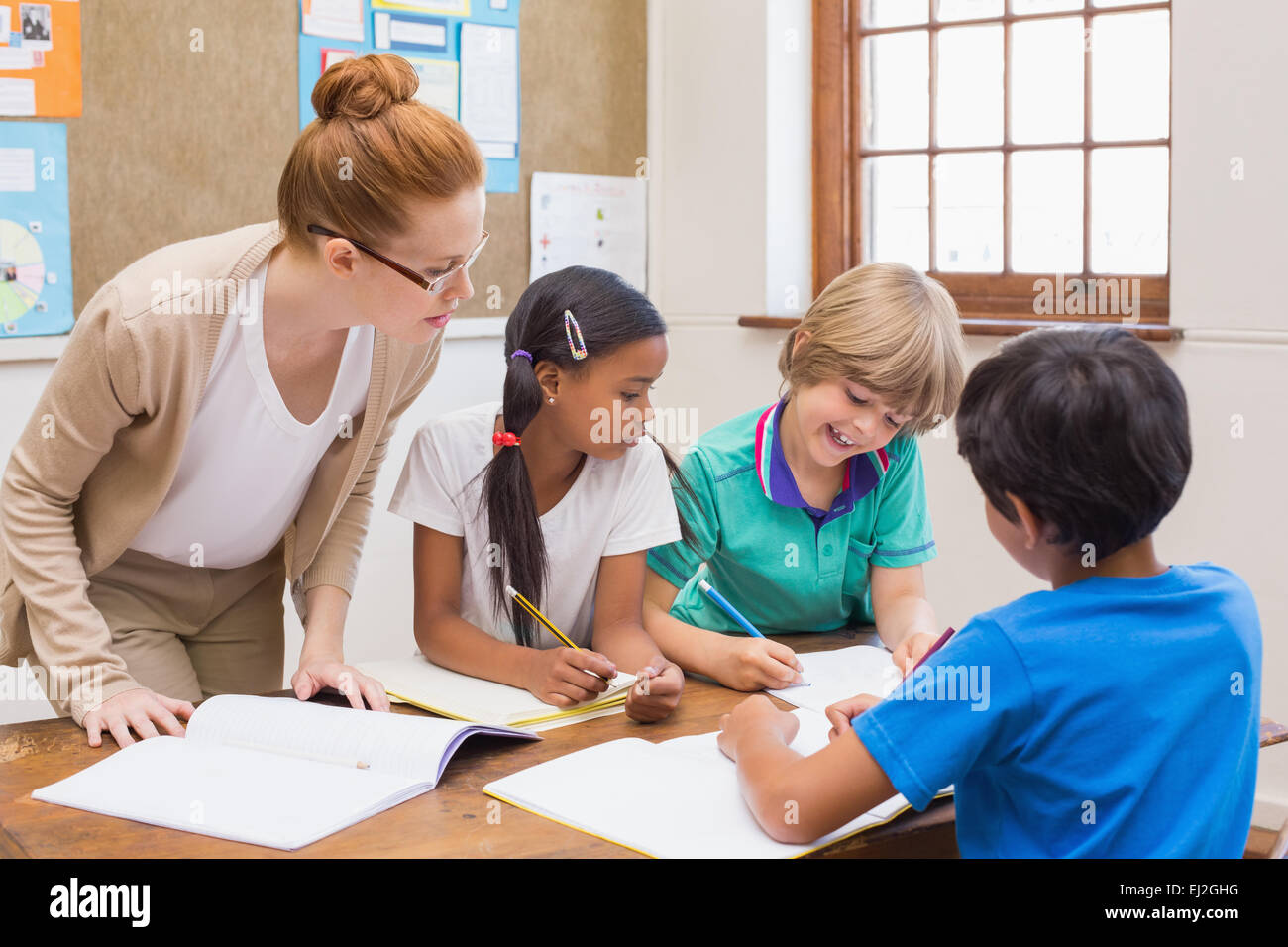 Teacher and pupils working at desk together Stock Photo - Alamy