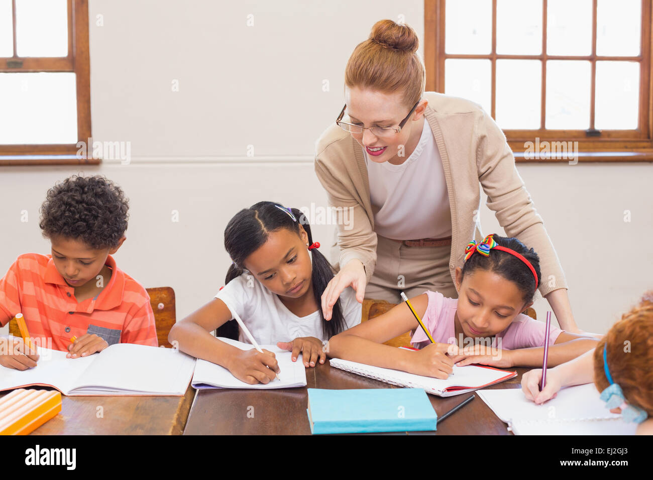 Cute pupils getting help from teacher in classroom Stock Photo - Alamy