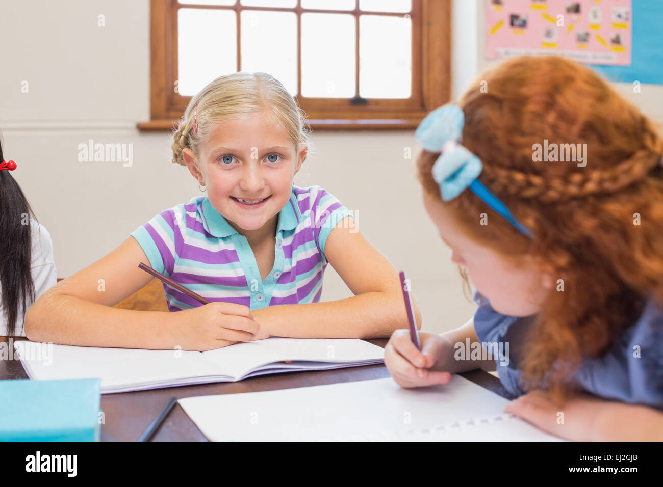 Cute pupils writing at desk in classroom Stock Photo - Alamy