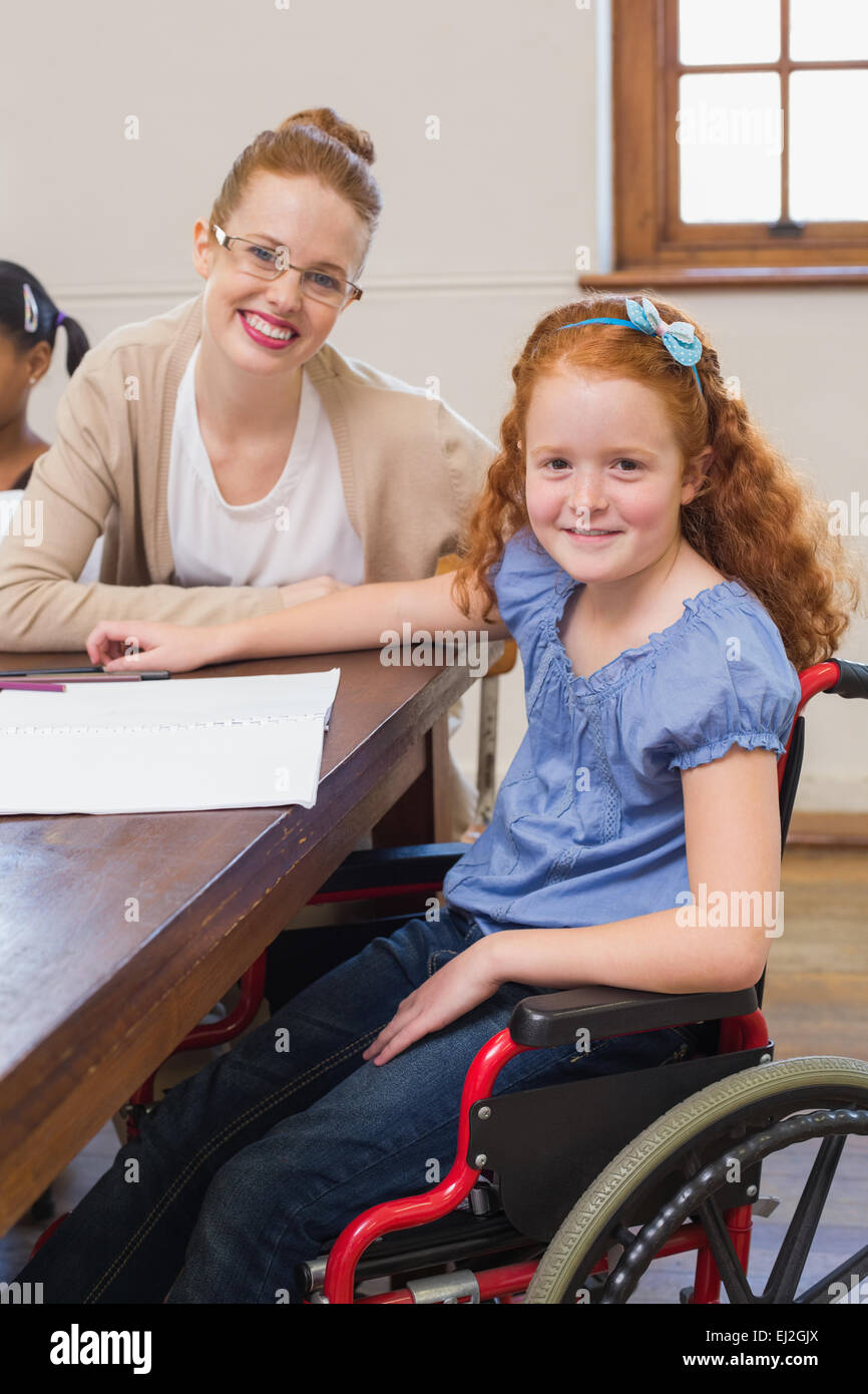 Pretty teacher helping pupil in classroom Stock Photo - Alamy