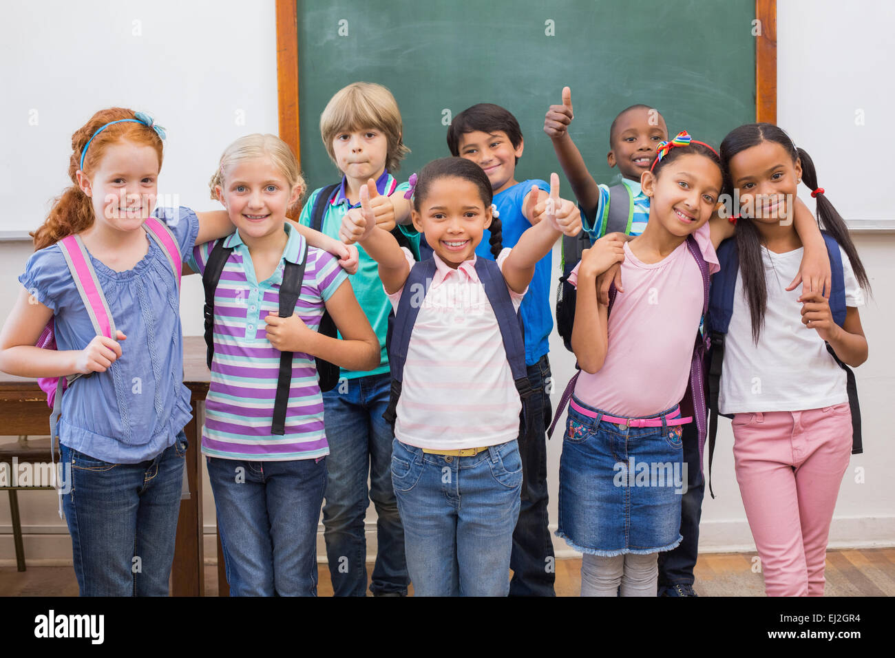 Cute pupils smiling at camera in classroom Stock Photo - Alamy