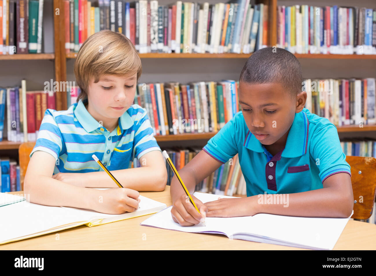 Cute pupils drawing in library Stock Photo - Alamy