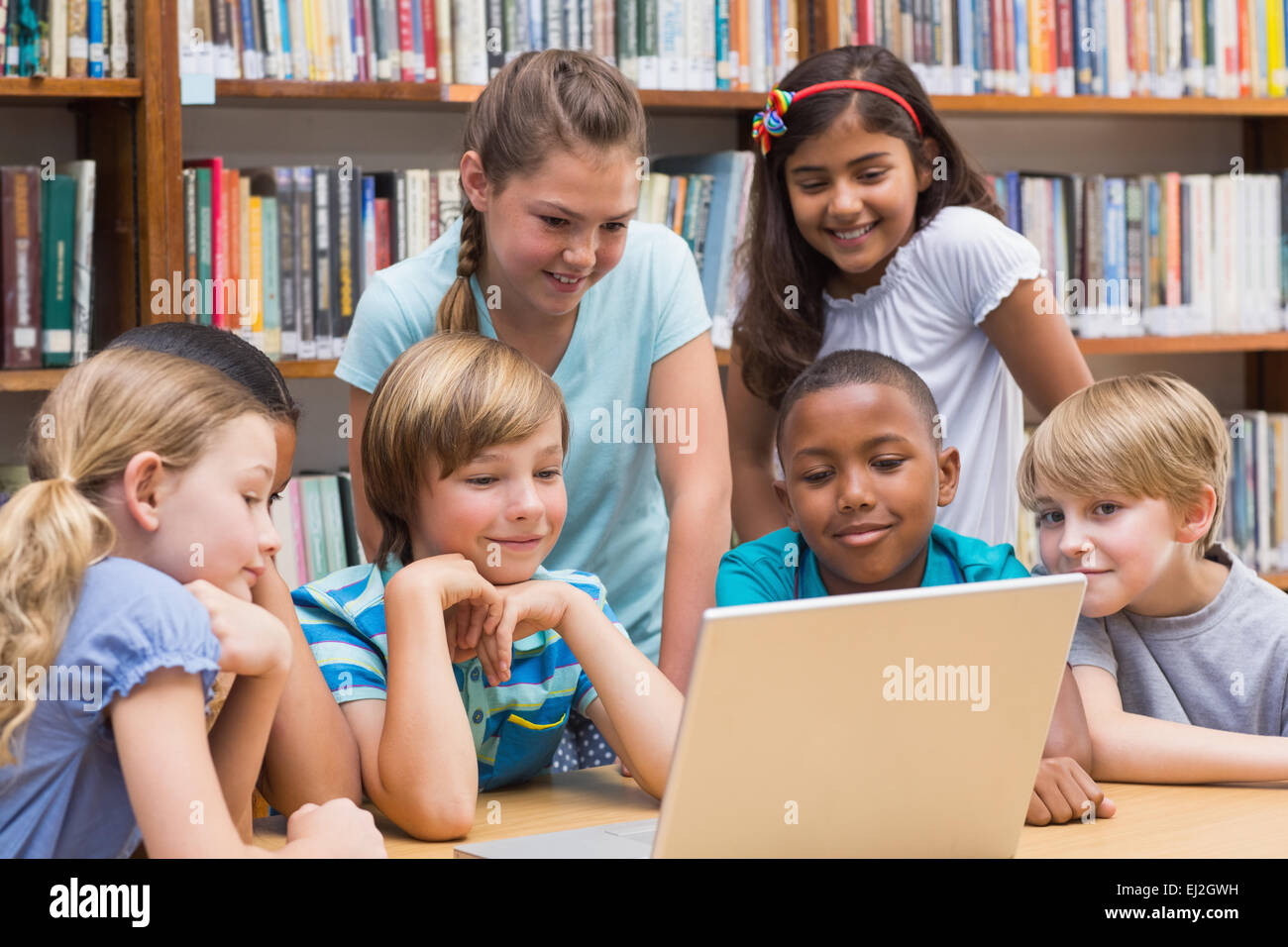 Cute pupils using tablet computer in library Stock Photo - Alamy