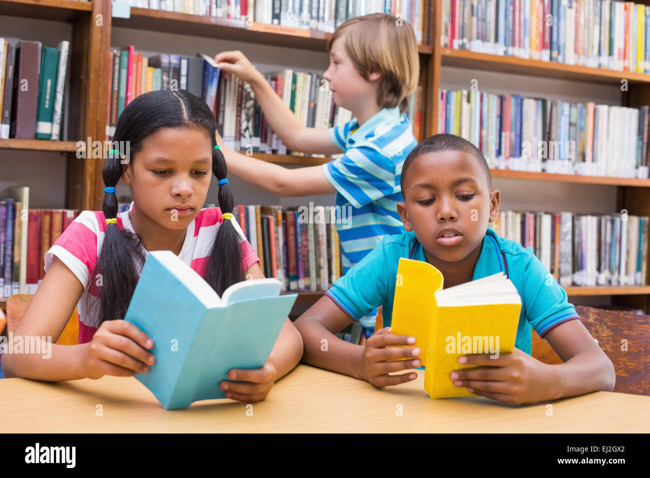 Cute pupils reading in library Stock Photo - Alamy