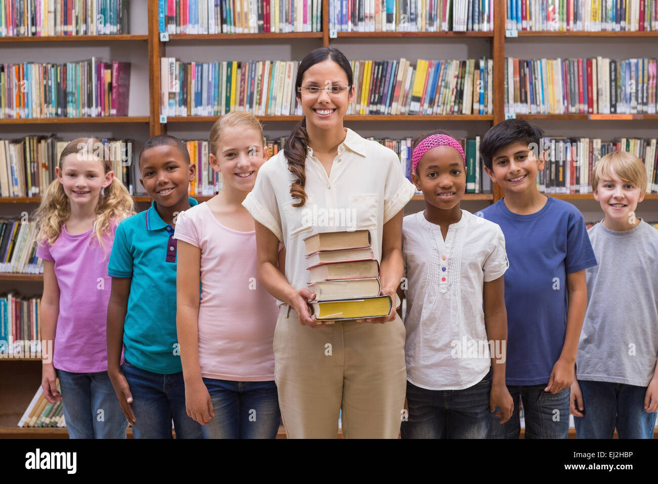 Cute pupils and teacher having class in library Stock Photo - Alamy