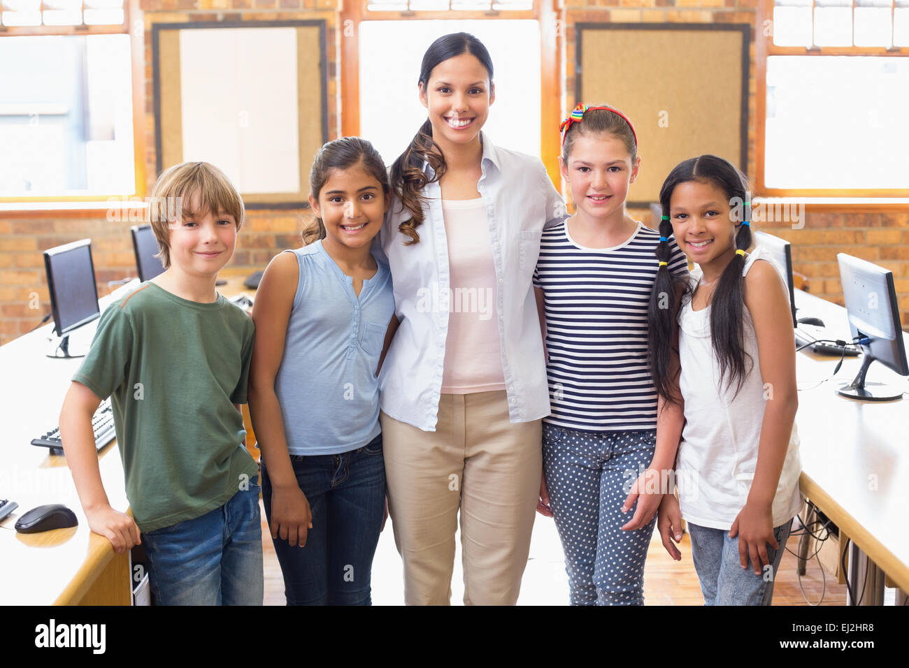 Cute pupils and teacher smiling at camera in computer class Stock Photo ...