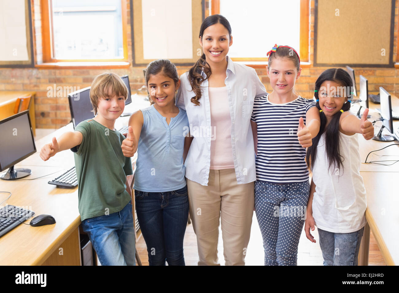 Cute pupils and teacher smiling at camera in computer class Stock Photo ...