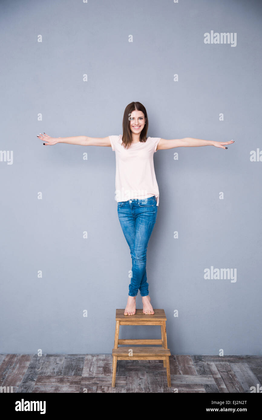 Smiling young woman standing on the chair Stock Photo - Alamy