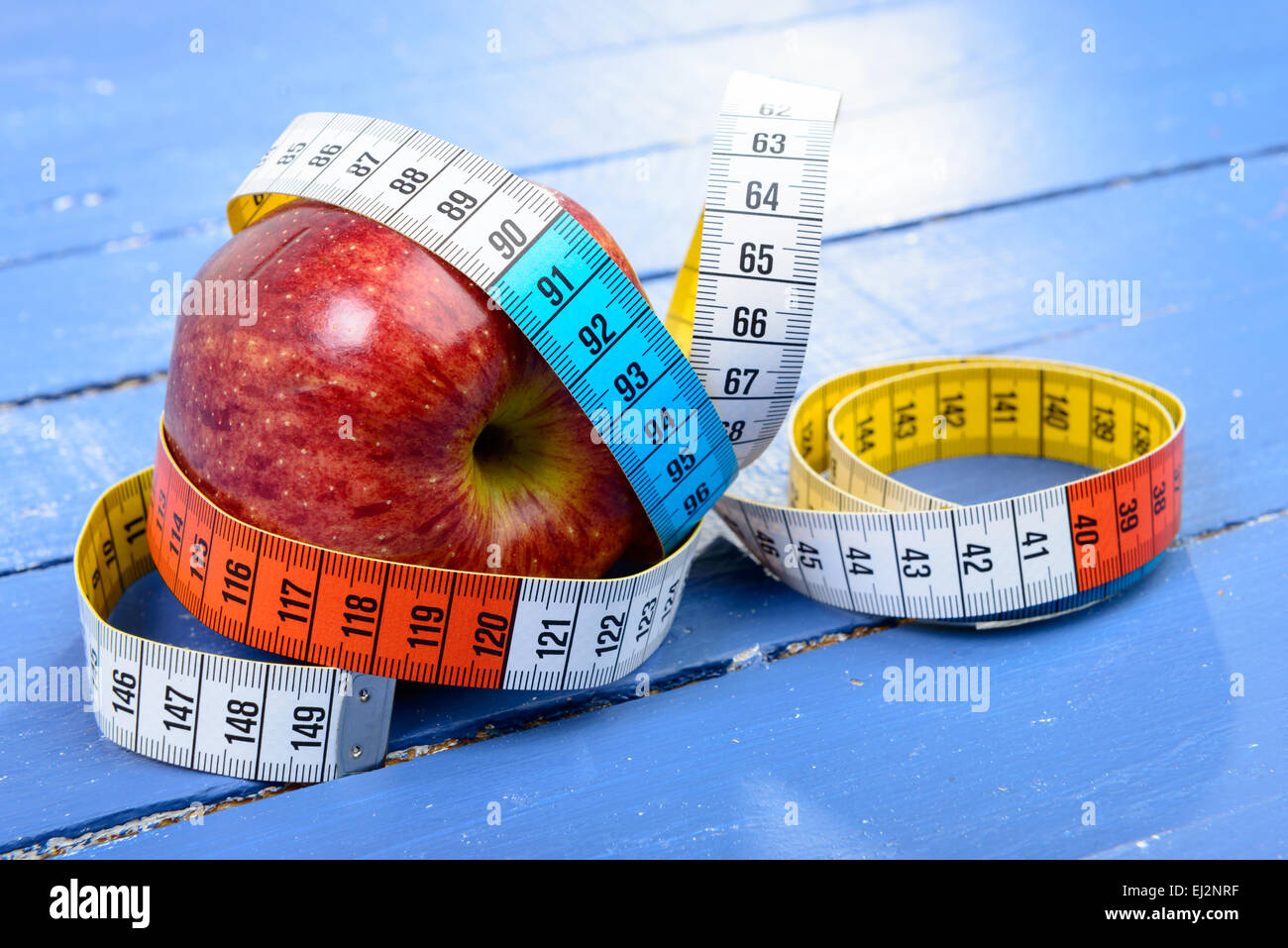 one meter ribbon around apple on the blue table Stock Photo - Alamy