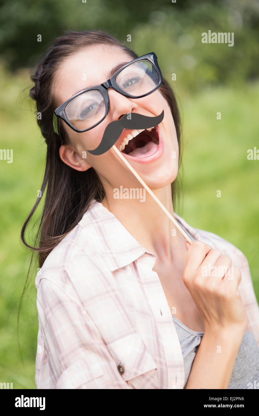 Pretty brunette smiling at camera with fake mustache Stock Photo - Alamy