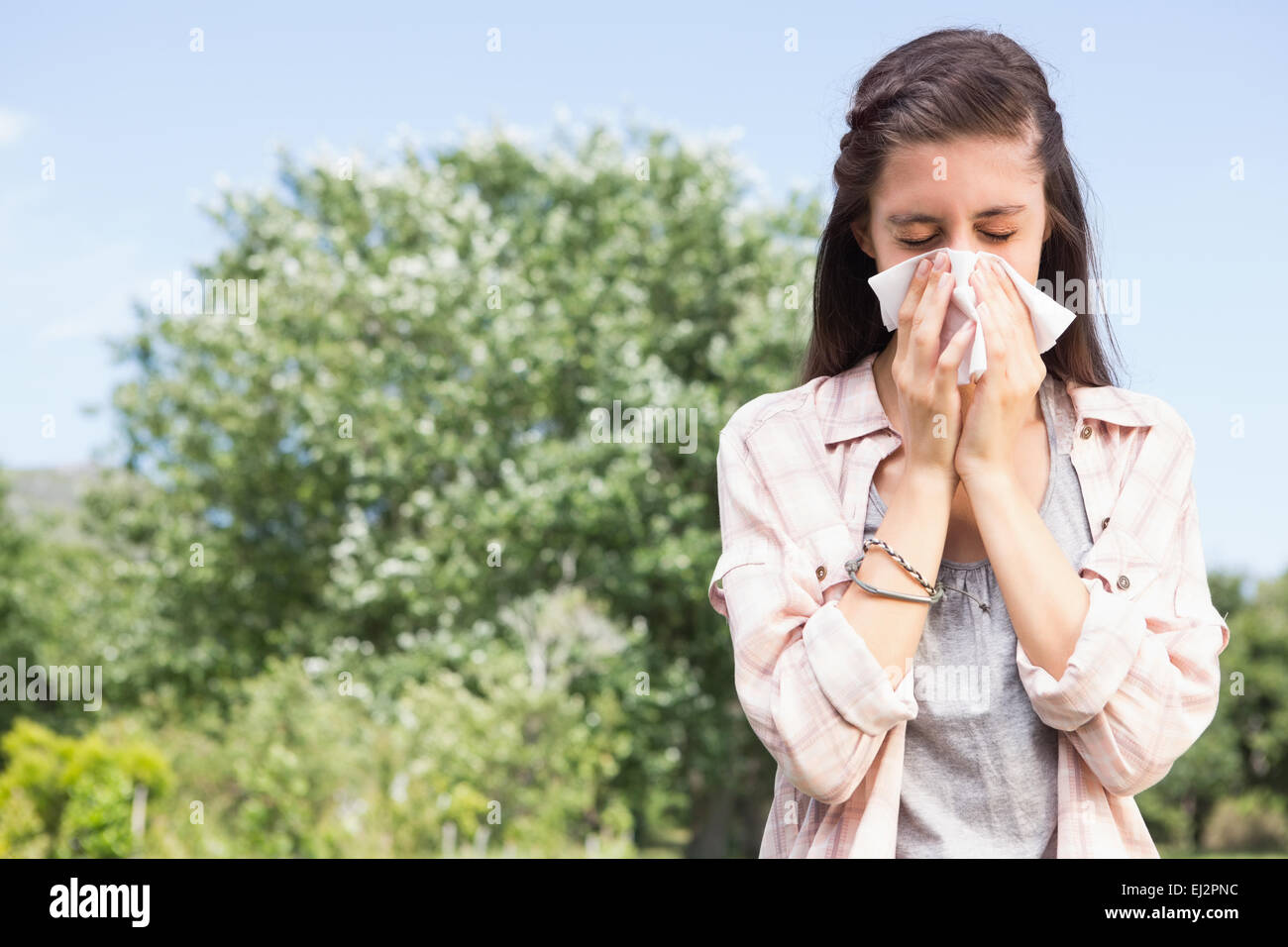 Pretty brunette blowing her nose Stock Photo - Alamy