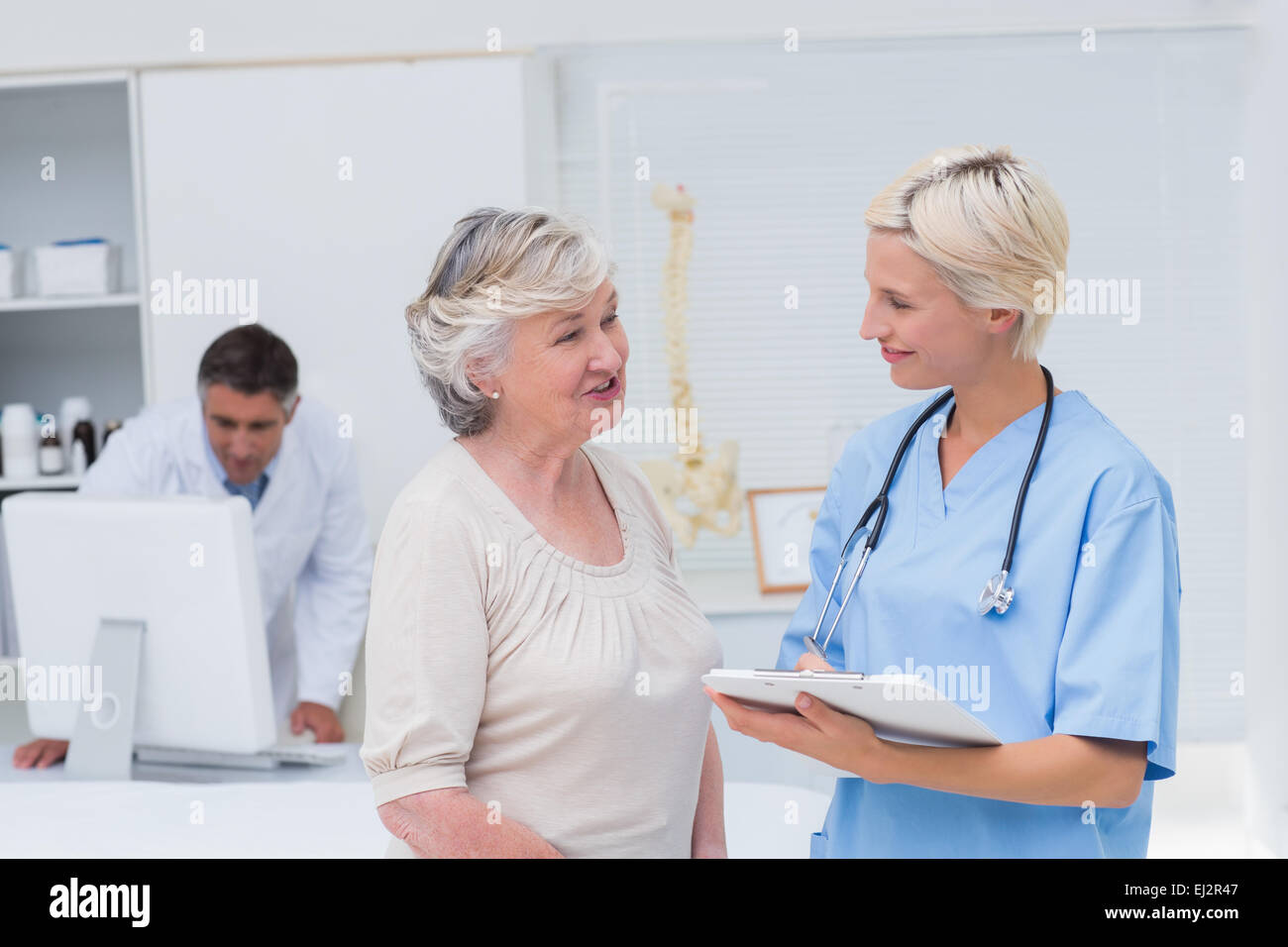 Nurse discussing with patient while doctor using computer Stock Photo ...