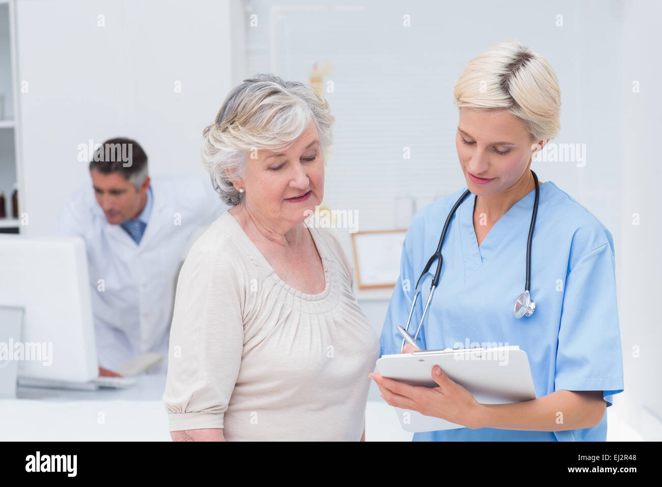 Nurse communicating with patient while doctor using computer Stock ...