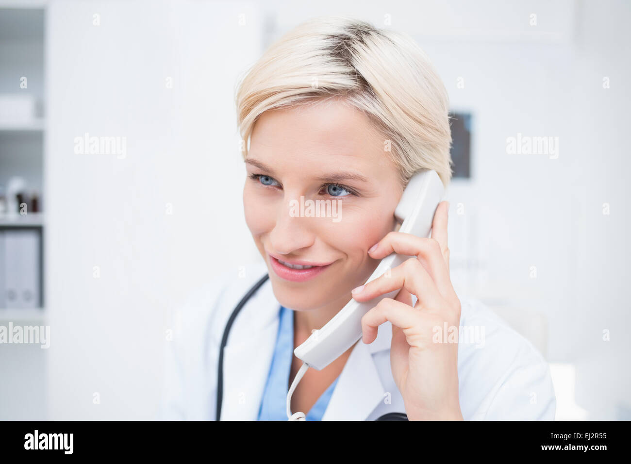 Doctor using telephone while looking away Stock Photo - Alamy
