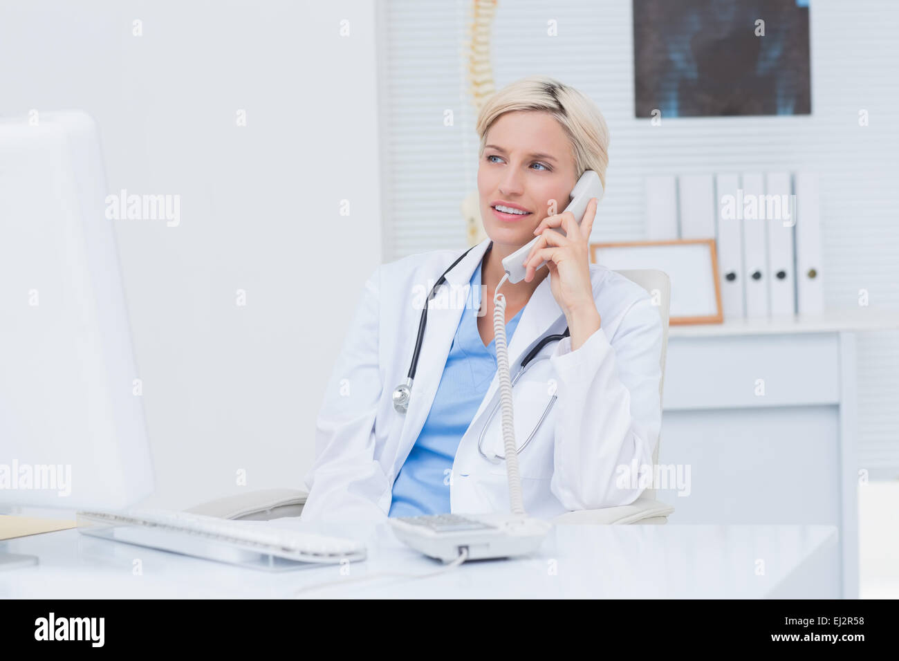 Doctor using telephone at table Stock Photo - Alamy