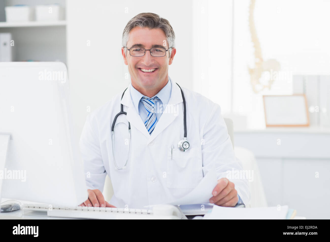 Happy male doctor reviewing documents at table Stock Photo - Alamy