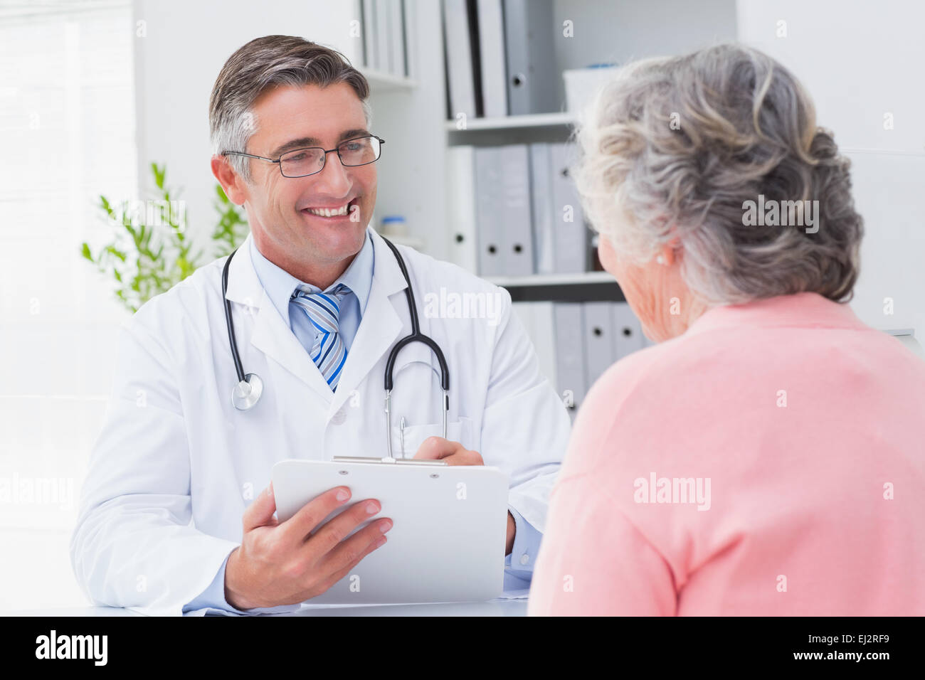 Smiling doctor writing prescriptions for patient Stock Photo - Alamy