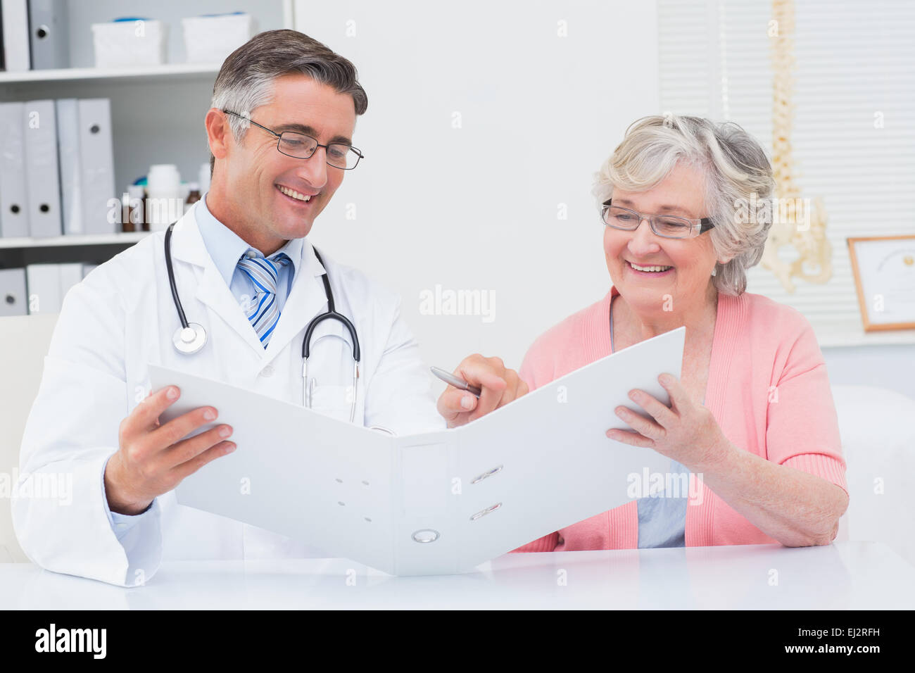 Doctor and female patient looking at reports in file Stock Photo - Alamy