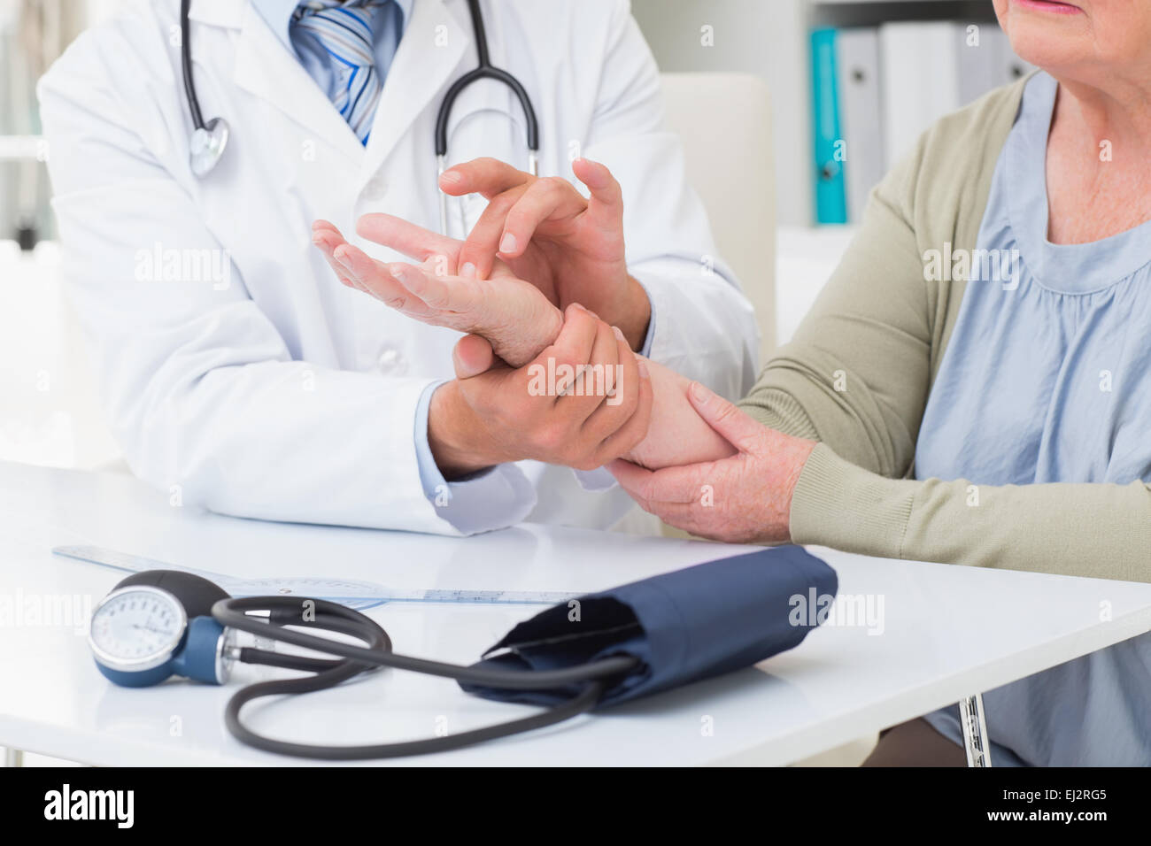 Doctor examining patients hand at table Stock Photo - Alamy