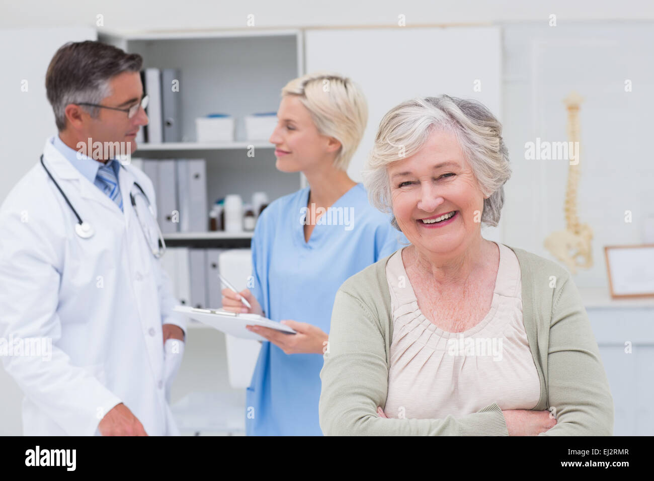 Patient smiling while doctor and nurse discussing in background Stock ...