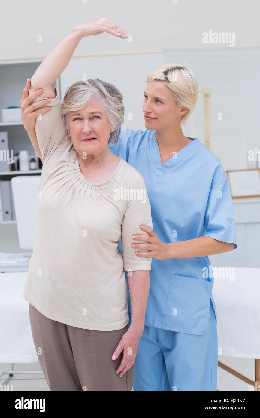 Nurse assisting senior patient in raising arm Stock Photo - Alamy