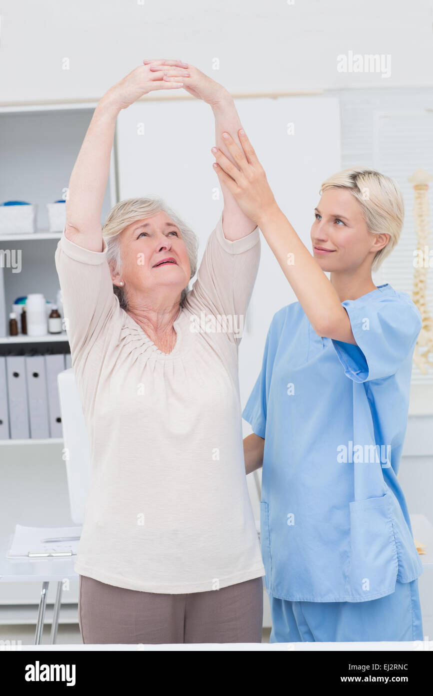 Nurse assisting female patient in raising arms Stock Photo - Alamy