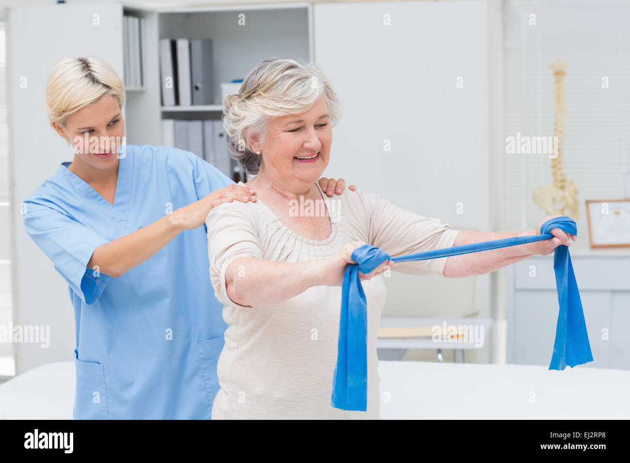 Nurse assisting senior patient in exercising with resistance band Stock ...