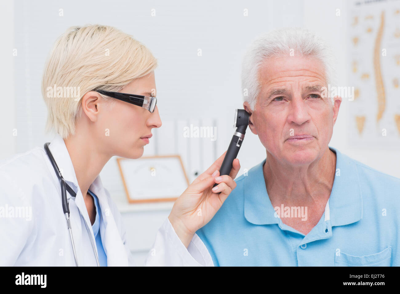 Doctor examining male patients ear with otoscope Stock Photo - Alamy