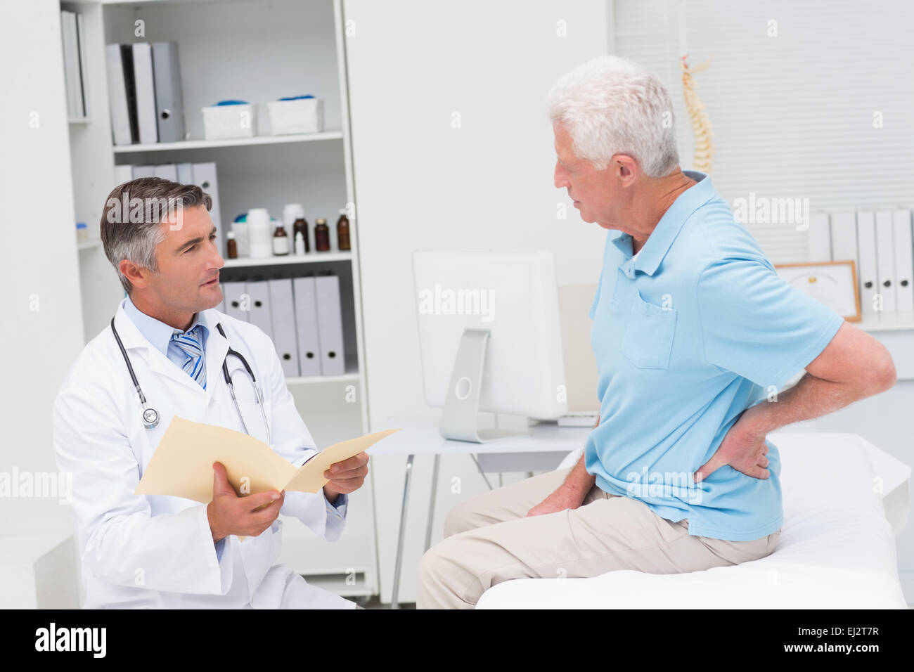 Doctor discussing reports with patient suffering from backache Stock ...