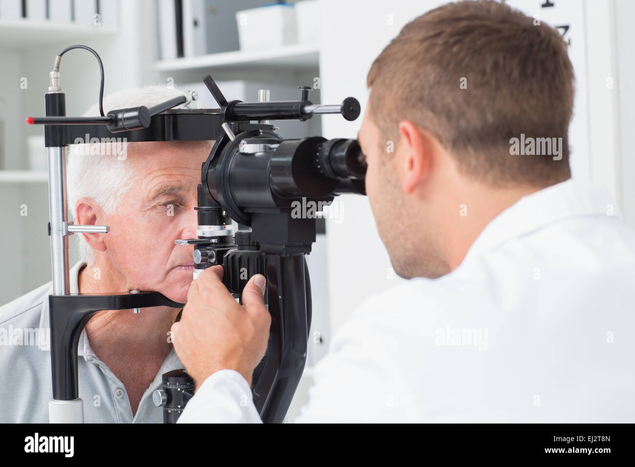 Optician examining senior patients eyes through slit lamp Stock Photo - Alamy