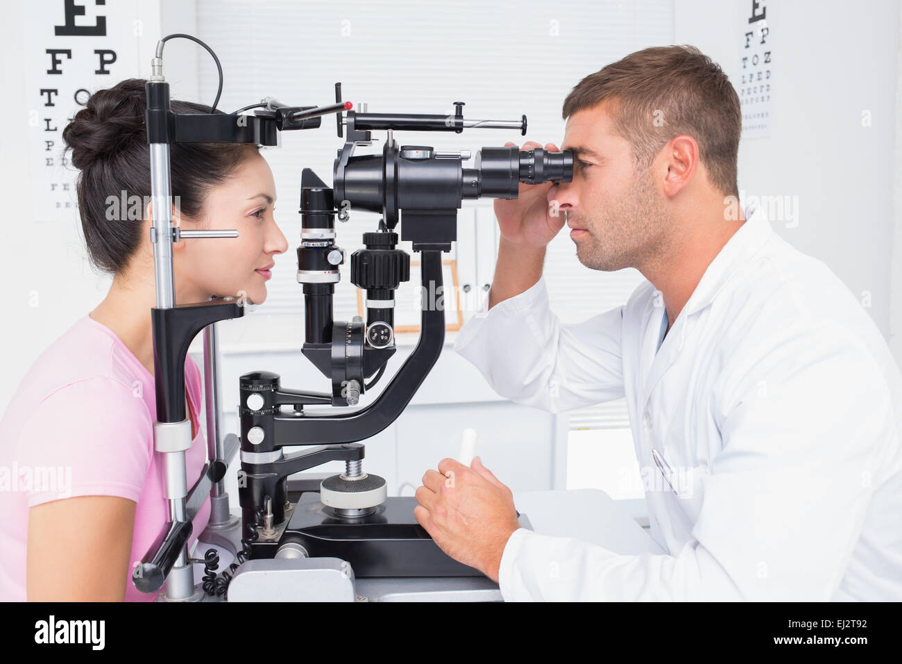 Optician examining womans eyes through slit lamp Stock Photo - Alamy