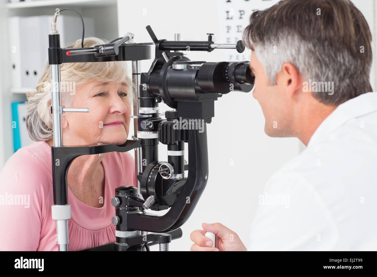 Optician examining senior female patient through slit lamp Stock Photo - Alamy
