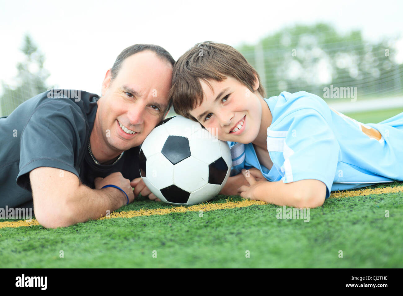 A young soccer player with father Stock Photo - Alamy