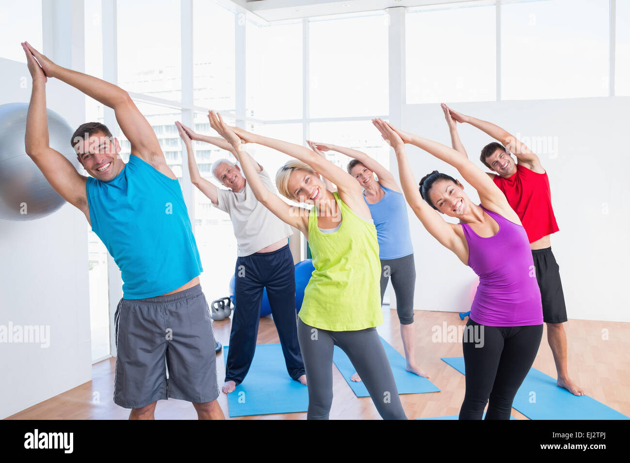 Happy people doing stretching exercise in yoga class Stock Photo - Alamy