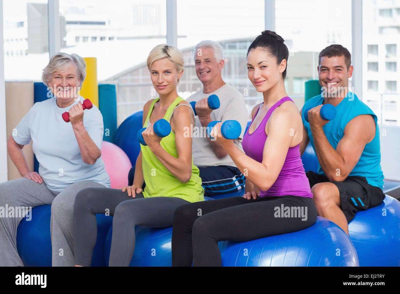 People working out with dumbbells in gym class Stock Photo - Alamy