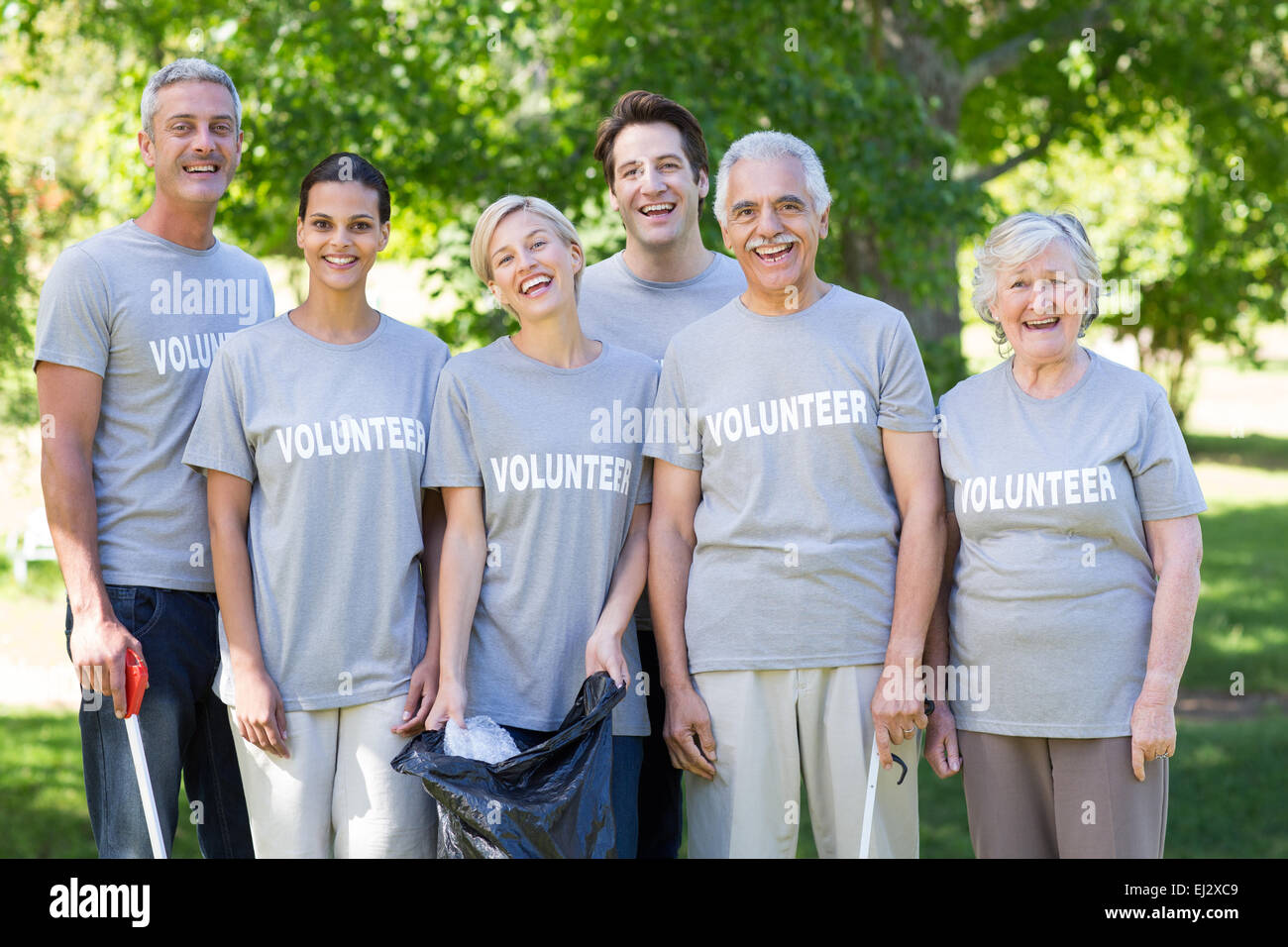Happy volunteer family smiling at the camera Stock Photo - Alamy