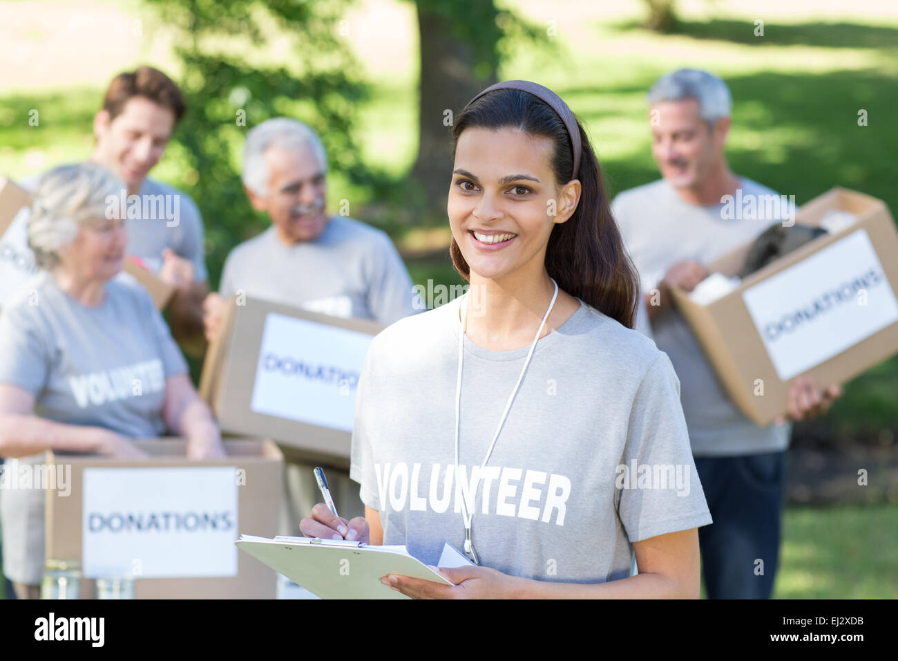 Smiling volunteer brunette writing on cipboard Stock Photo - Alamy